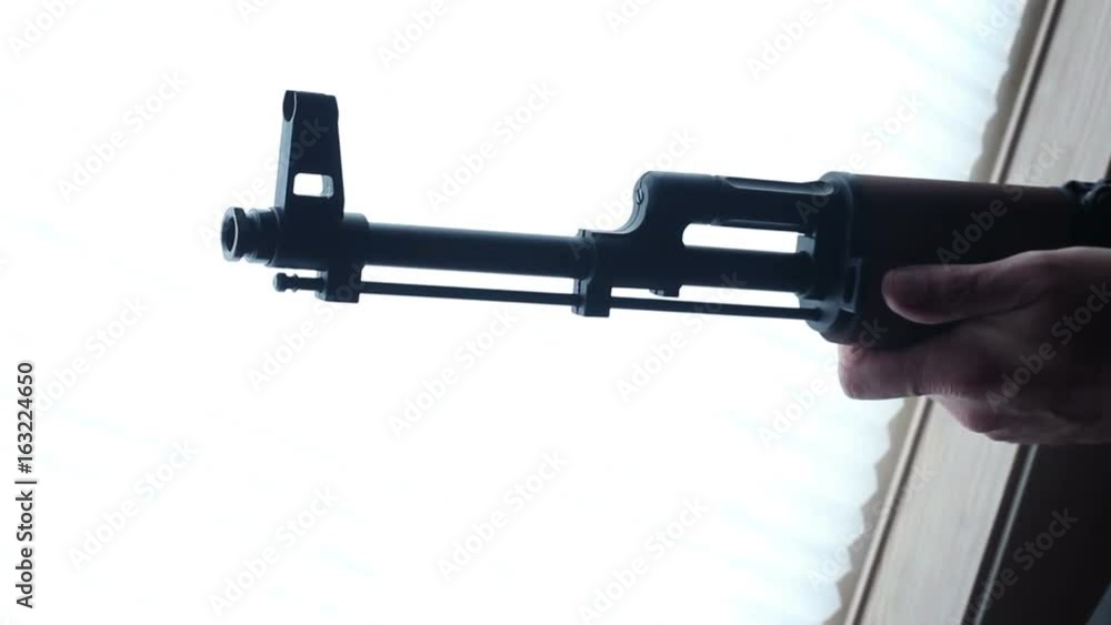 An AK-47 Kalashnikov assault rifle is raised in ambient home setting ...