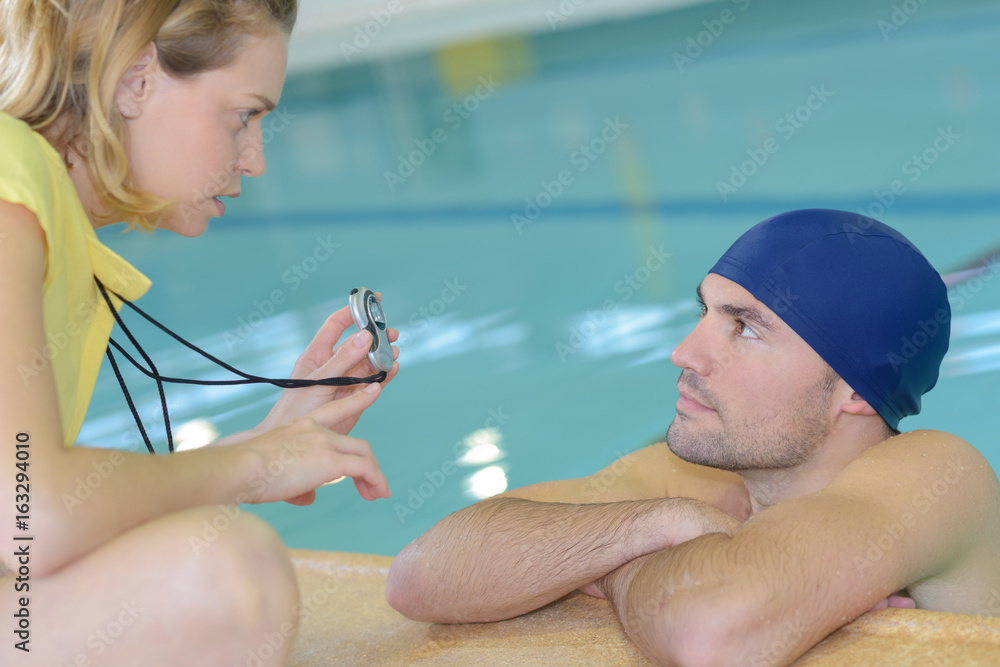Disappointed coach showing swimmer time on stopwatch Stock Photo ...
