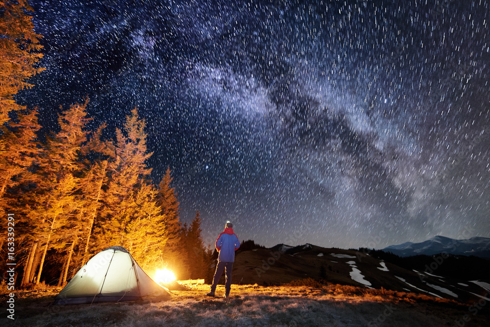 Male tourist have a rest in his camp near the forest at night. Man ...