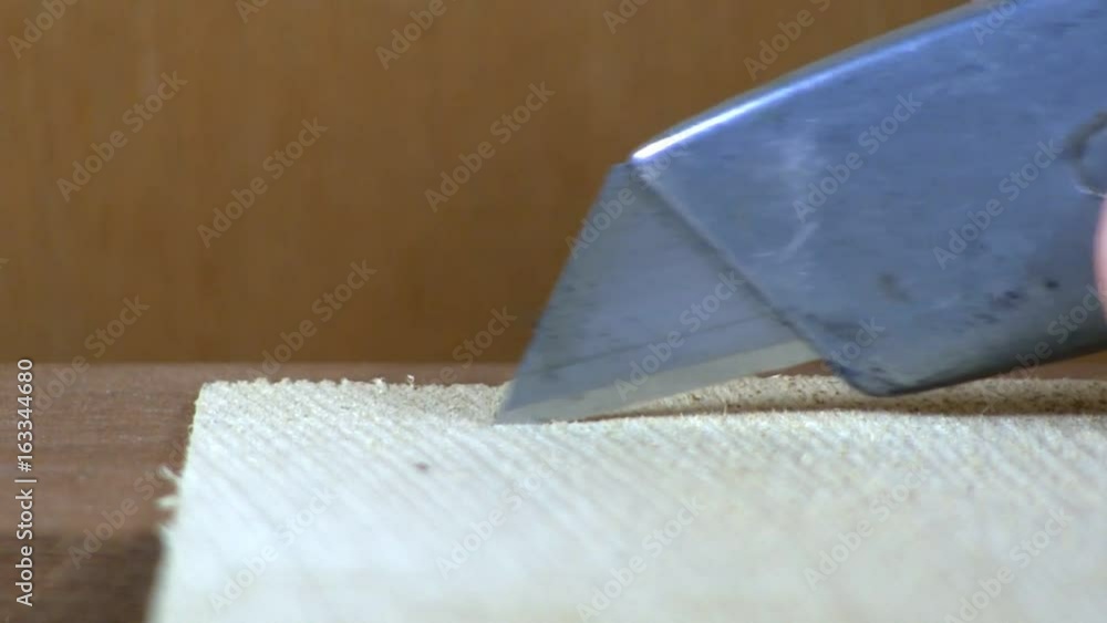 A utility knife is used to cut and trim a cedar shingle for ...