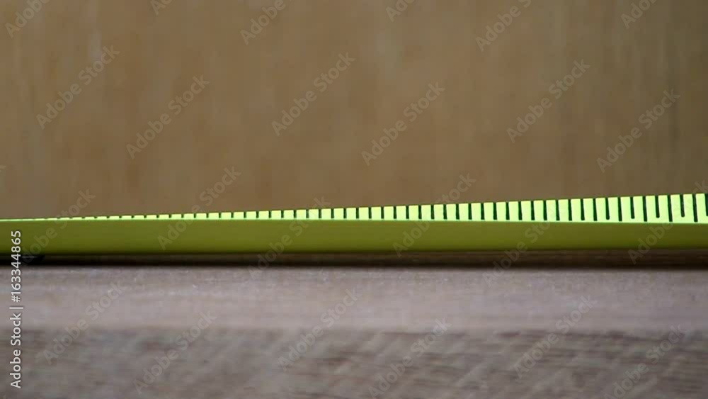 A tape measure is used to draw tick marks in maple board for cutting ...