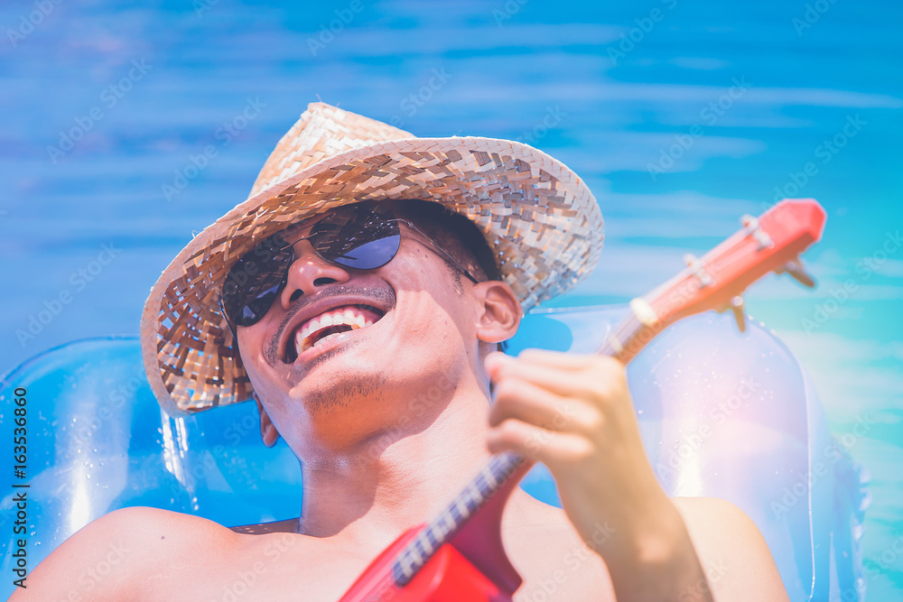 close up of man with ukulele smile and relaxing on the air mattress in ...