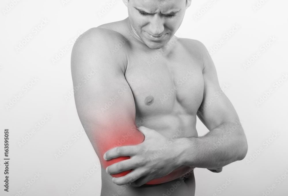 Front view of a young man holding his elbow in pain, isolated on white ...