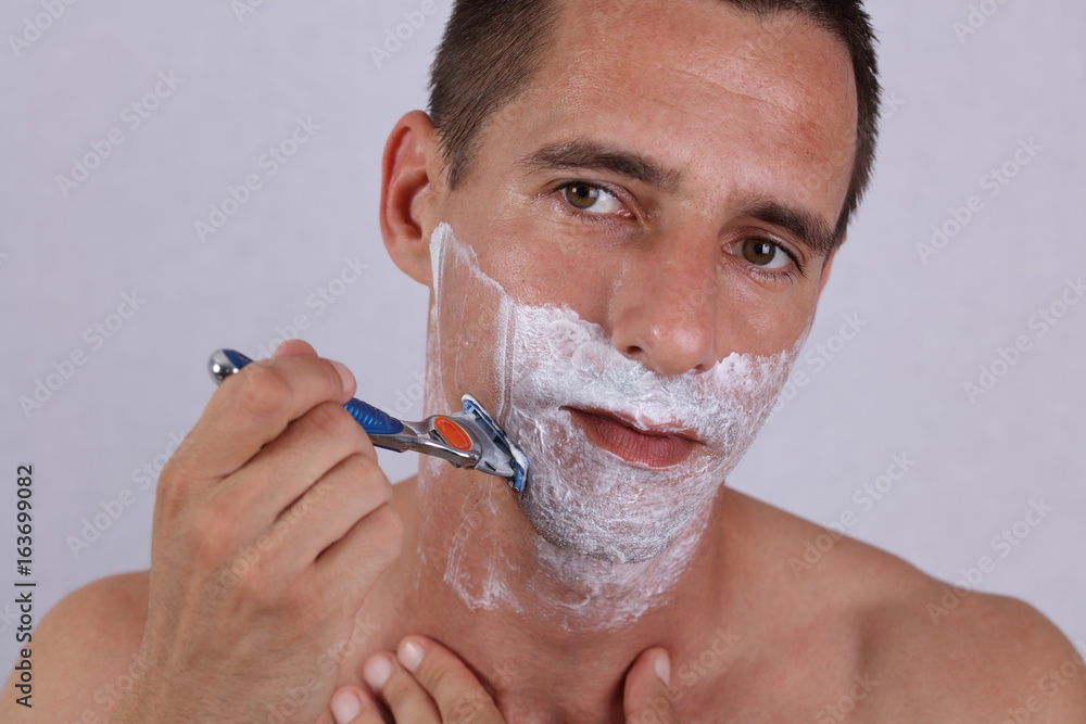Man shaving his face with the razor blade through shave foam. Male skin ...