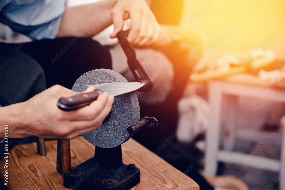 master sharpens the knife by tradition on a hand grindstone. Concept is ...