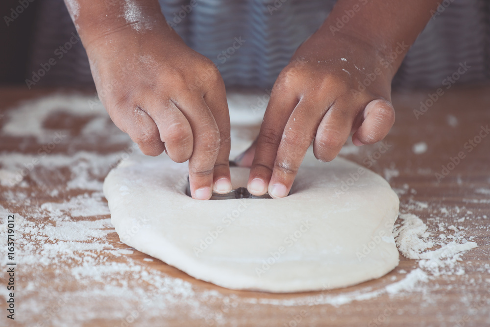 Little child girl hands prepares a dough for baking cookies in the ...
