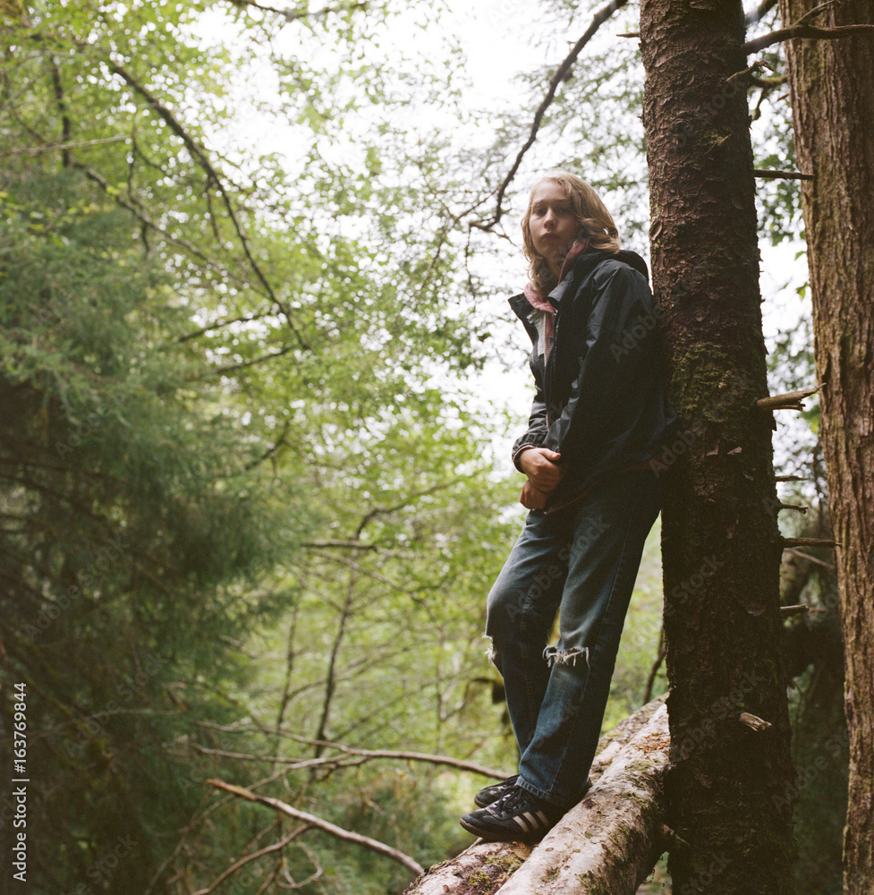 Portrait of boy, standing on log, leaning against tree Stock Photo ...