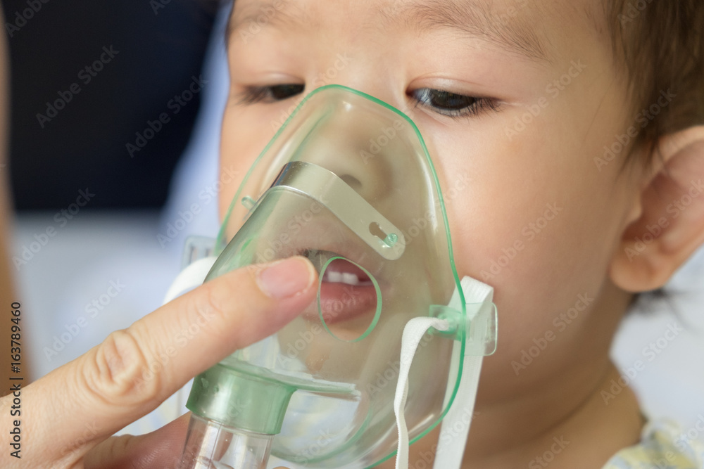 Asian child breathing through a steam nebulizer. Stock Photo | Adobe Stock