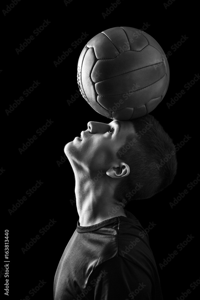 Caucasian young boy balances a classic leather soccer ball on his ...