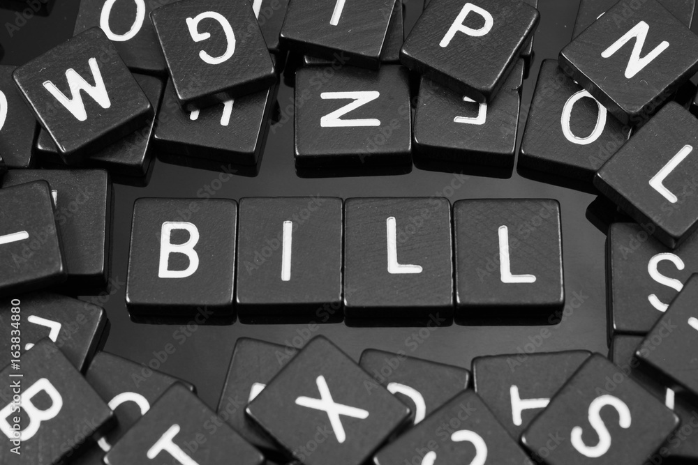 Black letter tiles spelling the word "bill" on a reflective background ...