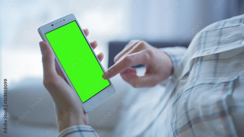 Young Woman in white jeans laying on couch uses smartphone with pre ...