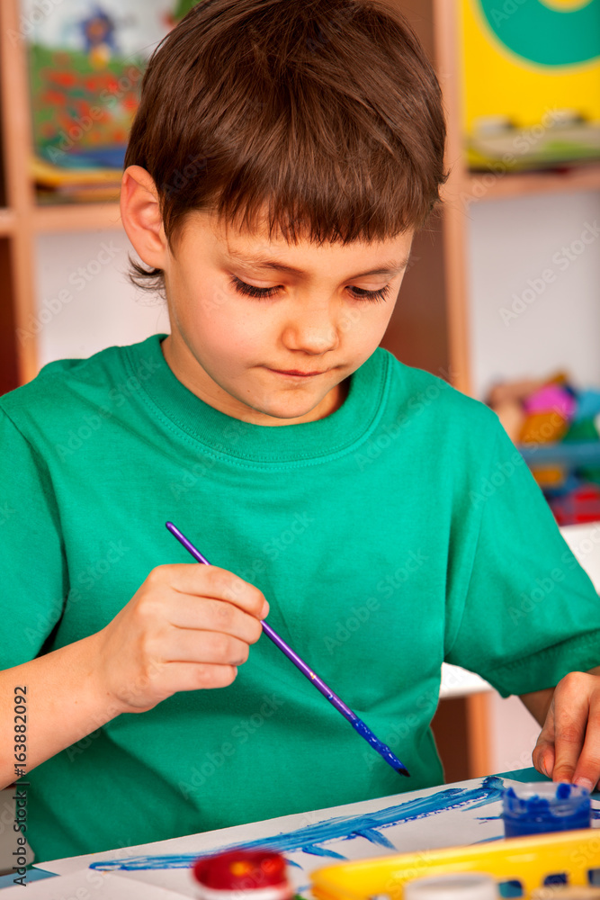 Small student boy painting in art school class. Child drawing by paints ...