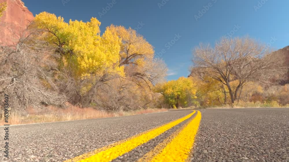 CLOSE UP Road with yellow line road marking leading trough red rock ...