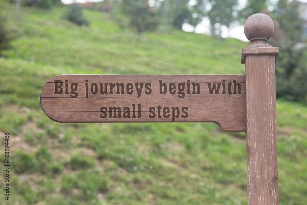 Big journeys begin with small steps text wooden sign with a forest ...