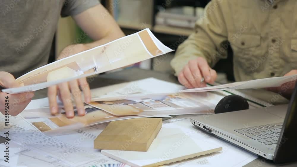 Designers discuss the project, which is depicted on colored sheets. Two ...