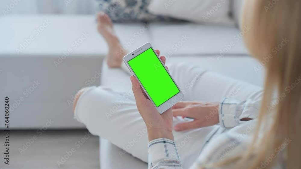 Young Woman in white jeans laying on couch holds SmartPhone with pre ...