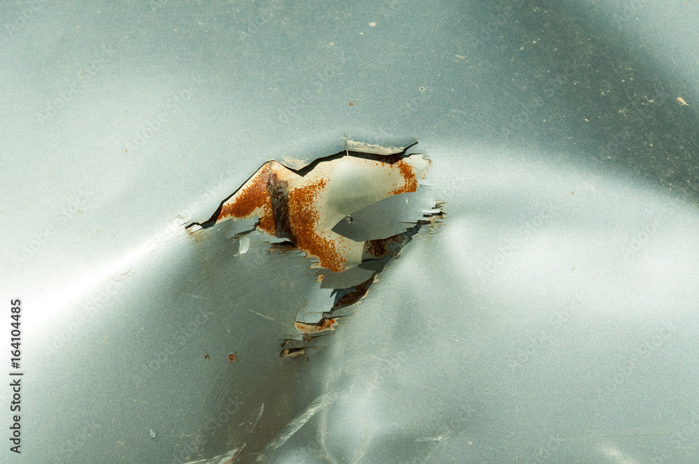 Damaged car hood in crash accident with rust and peeled paint. Close up ...