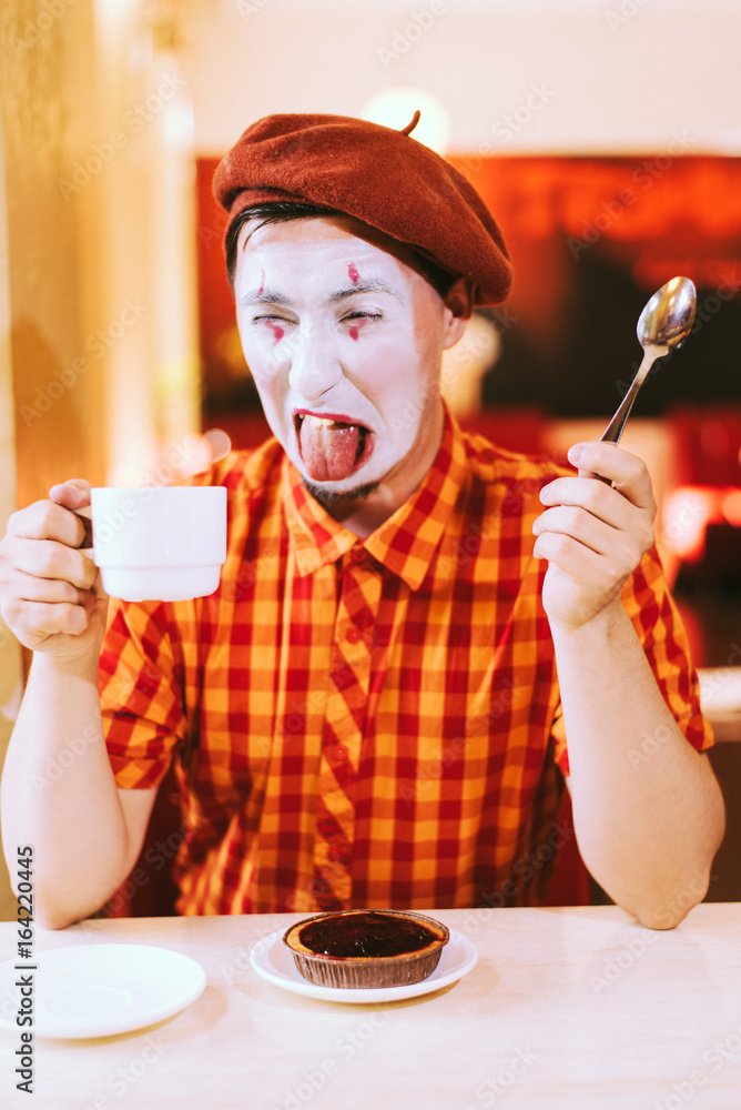 The clown is eating a cake in a cafe and his face is croaking. Stock ...