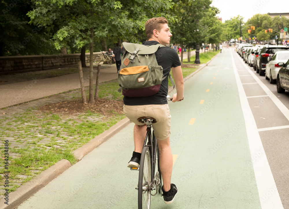 Back view of modern hipster man riding bike on bike lane and looksing ...