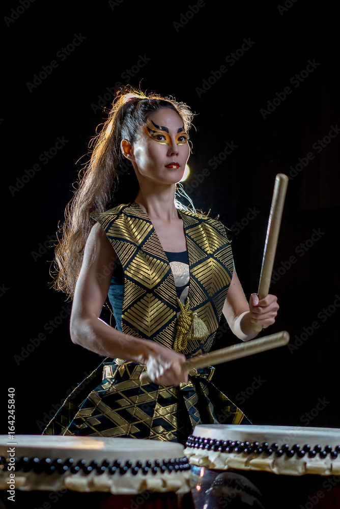 beautiful asian drummer girl with drumsticks, studio shot on a dark ...