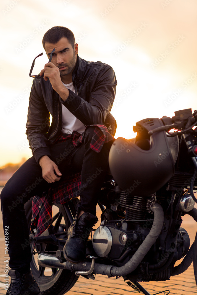 Handsome rider man with beard and mustache in black biker jacket put on ...
