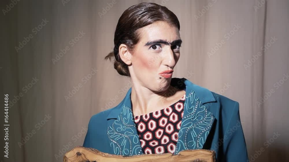 A funny ugly woman hiding behind a wooden frame with a green interior ...