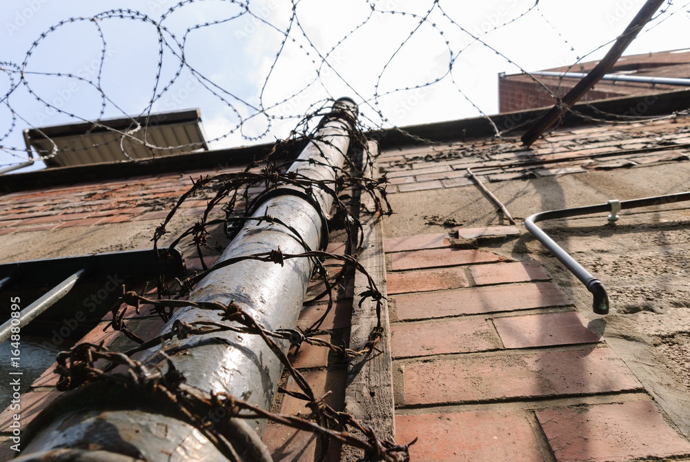 Barbed wire around a drainage downspout and along the top of a roof ...