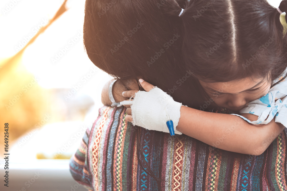 Sick child girl hugging and resting on her mother's shoulder in the ...