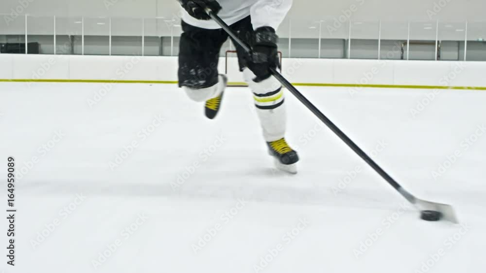 Tracking low-section shot of unrecognizable hockey player in white ...