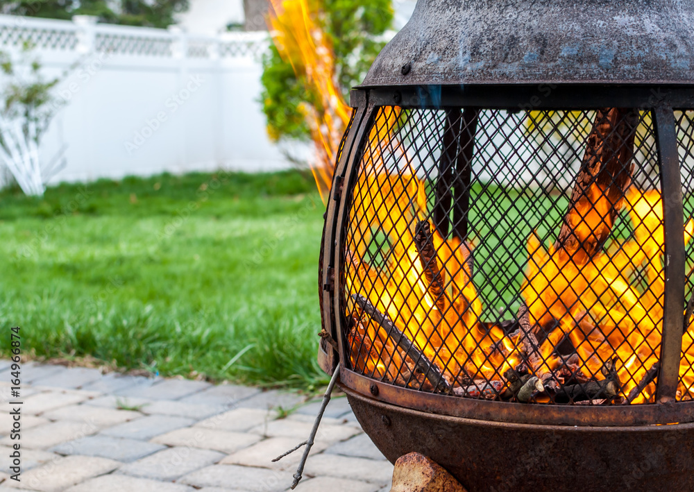 Outdoor fire pit with roaring fire. Chimera in backyard with strong ...