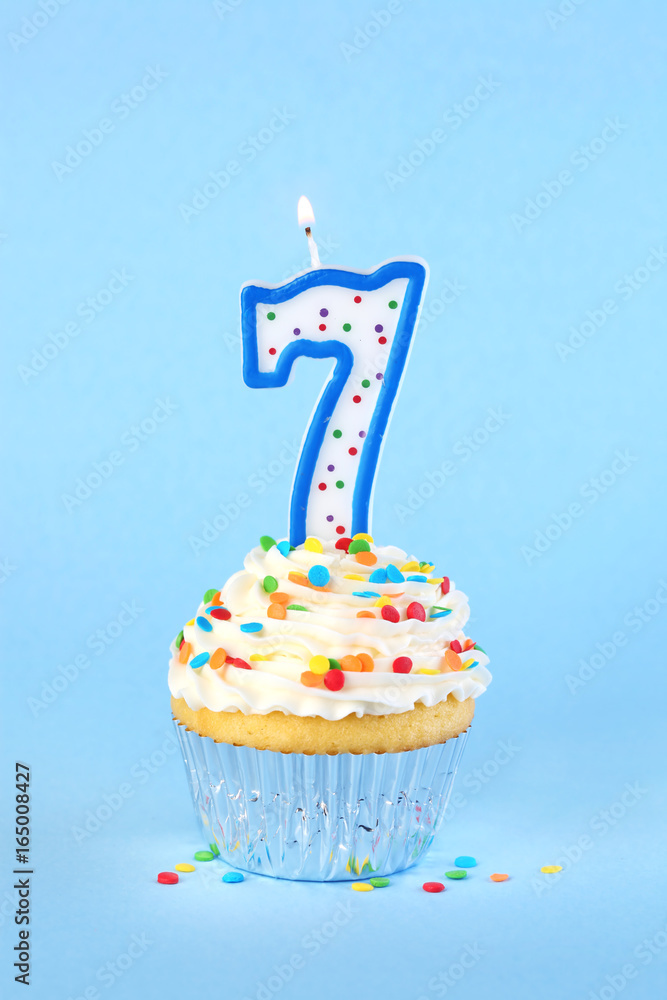 Iced birthday cupcake with with lit number 7 candle and sprinkles Stock ...