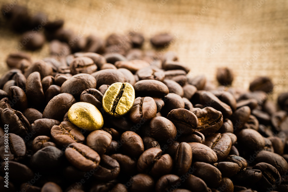 Gold coffee beans on a pile of coffee beans. The concept of luxury is ...