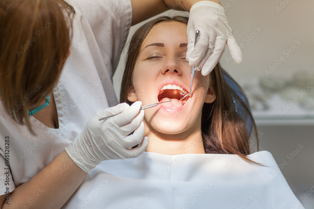 Dentist working in his office with a patient. Stock Photo | Adobe Stock