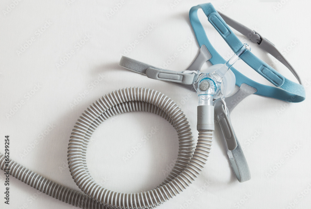 CPAP headgear mask, connecting with strap and hose laying on a bed ...