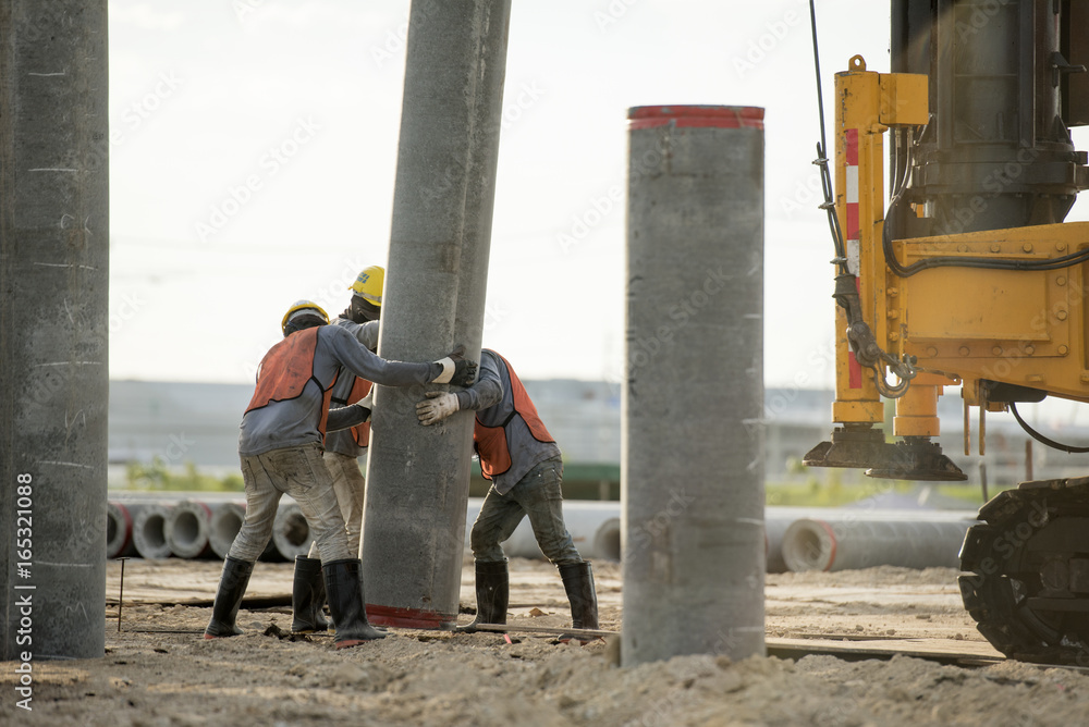 Construction team work in standard construction safety uniform installing precast concrete pile ...