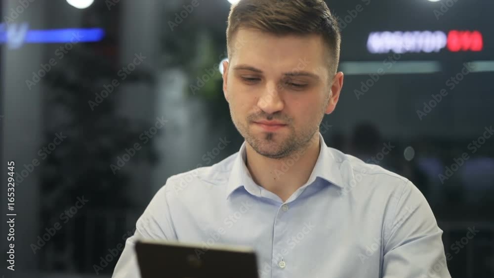 Front view young man sitting working using black laptop tablet device ...
