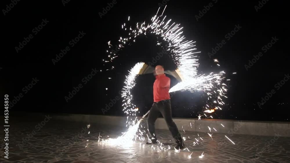 Man and women twist fiery circles on a fire show.Man and women does a ...