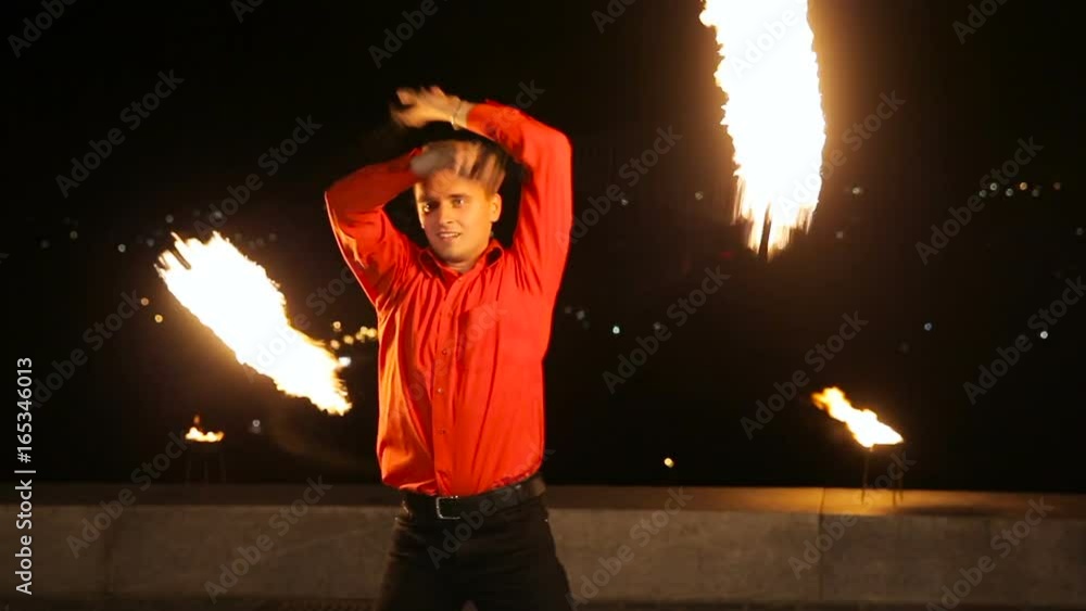 Artist man rotates the fireball.Man twist fiery circles on a fire show ...