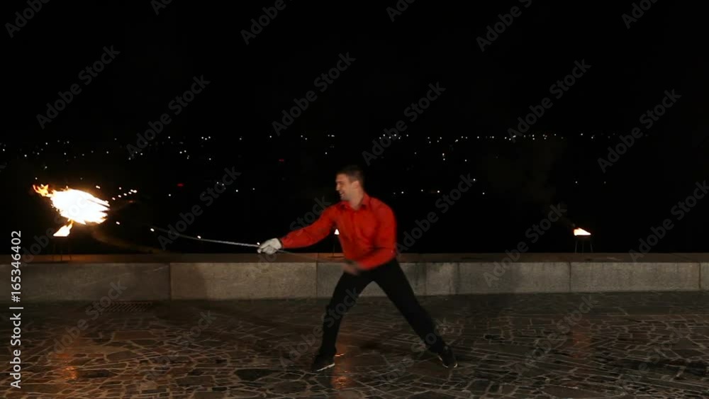 Artist man rotates the fireball.Man twist fiery circles on a fire show ...