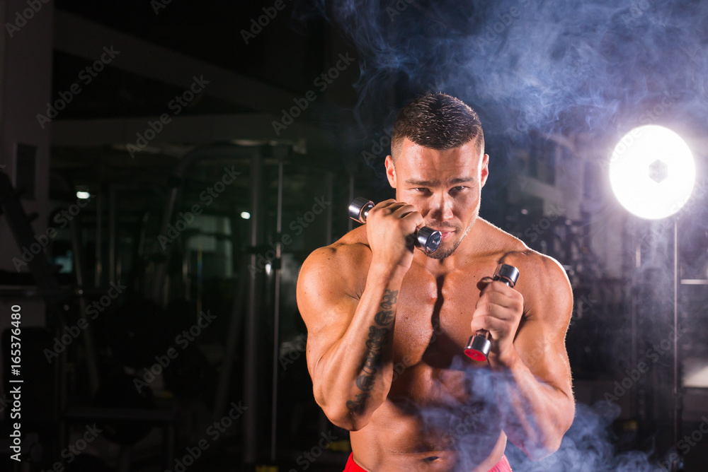 Sporty man doing boxing exercises, making direct hit with dumbbells ...