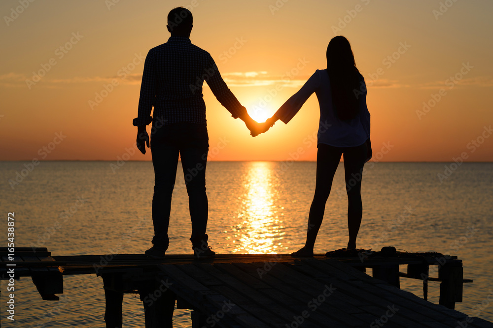 Two People Holding Hands In The Sunset
