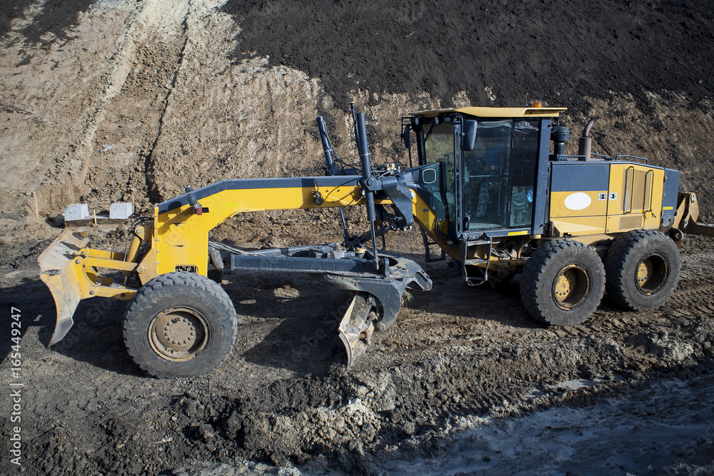 The construction machine Motor Grader level the ground with the ...