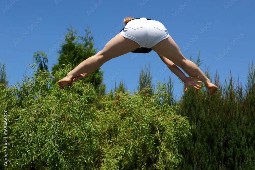 Teenager is practicing on a trampoline. Stock Photo | Adobe Stock