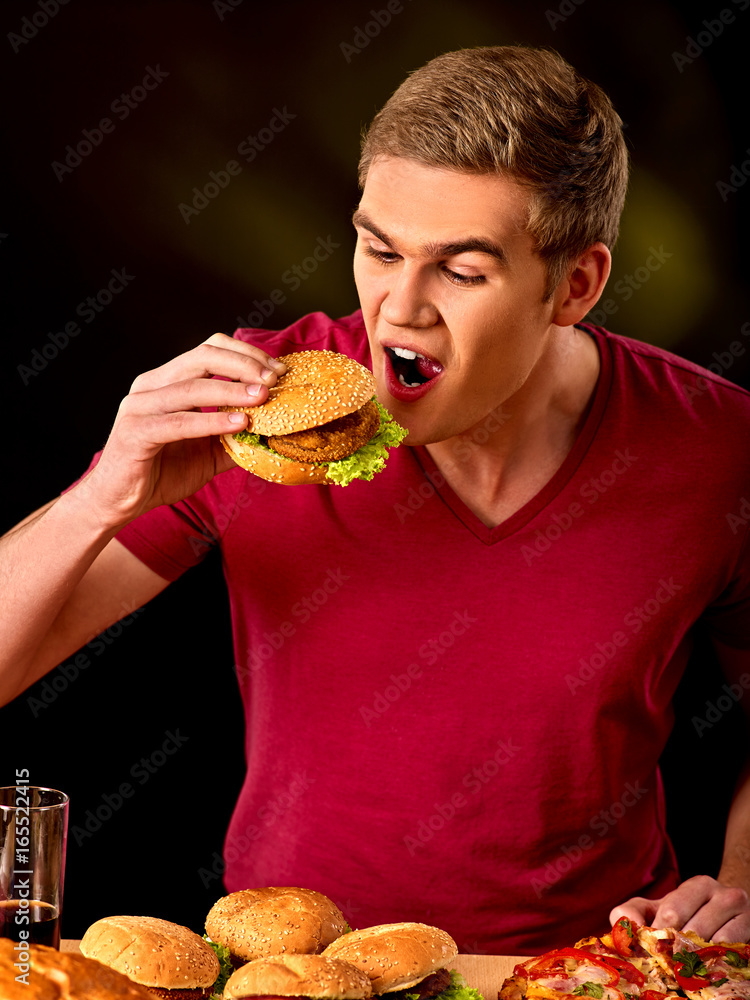 Man eating hamburger with pizza. Portrait of student consume fast food ...