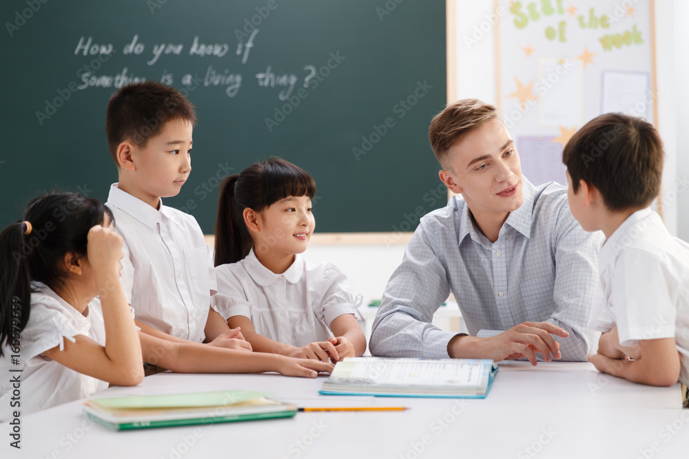 Male teacher helping students study in classroom Stock Photo | Adobe Stock