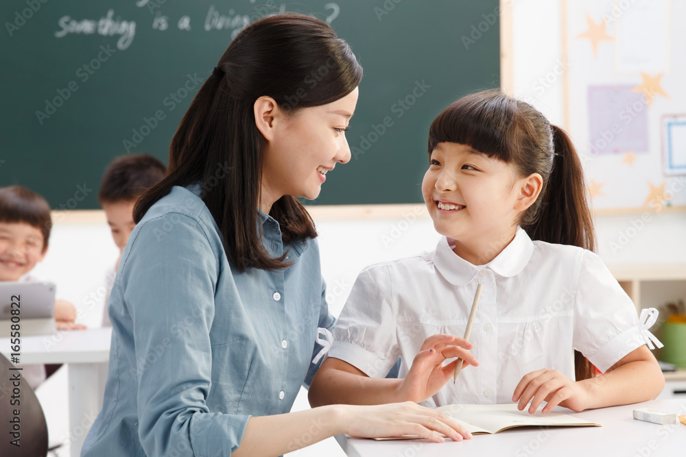 Female teacher helping student studying in classroom Stock Photo ...