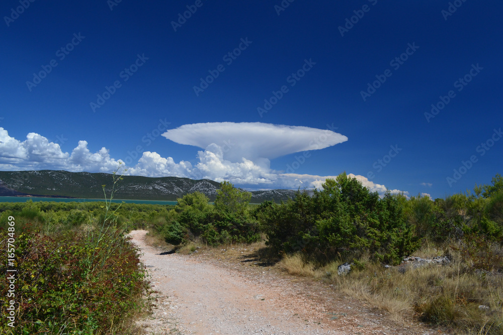 Cumulonimbus capillatus clouds, Vranksko jezero lake and road in ...