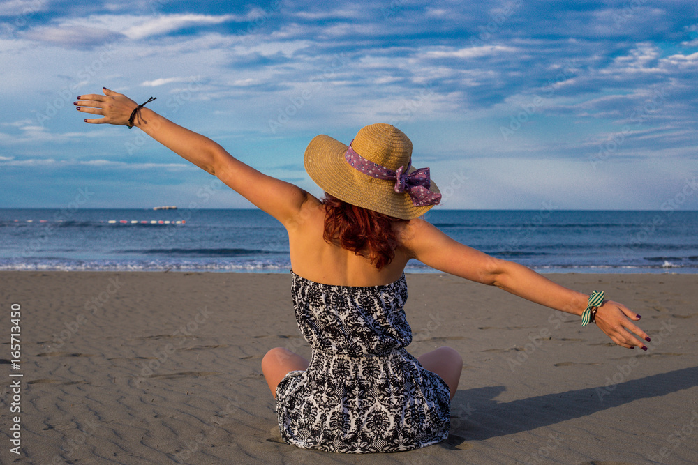 Beautiful girl woman in dress and hat sitting on the beach closeup with ...