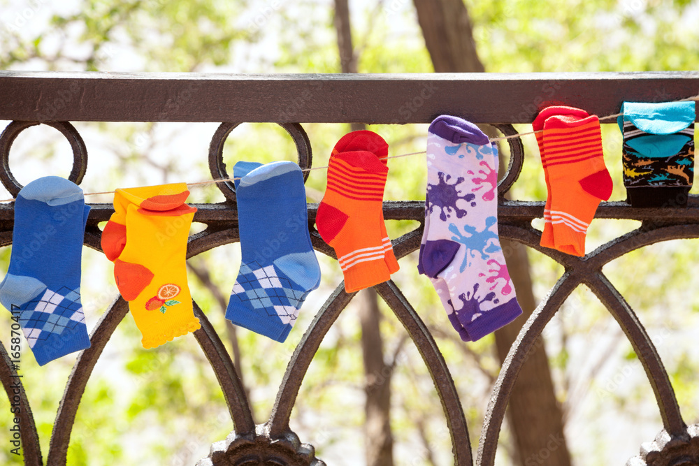Various colorful children socks hanging on a washing line outdoors ...