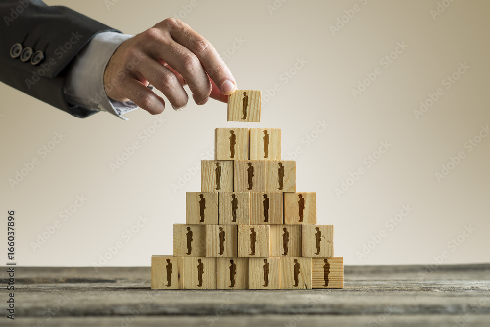 Businessman building a pyramid of wood blocks with people silhouettes ...